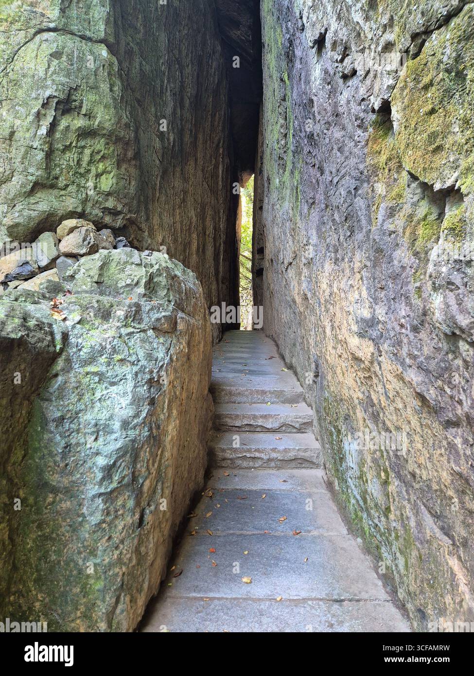 A narrow stone stairway passing through massive rock formations at a ...