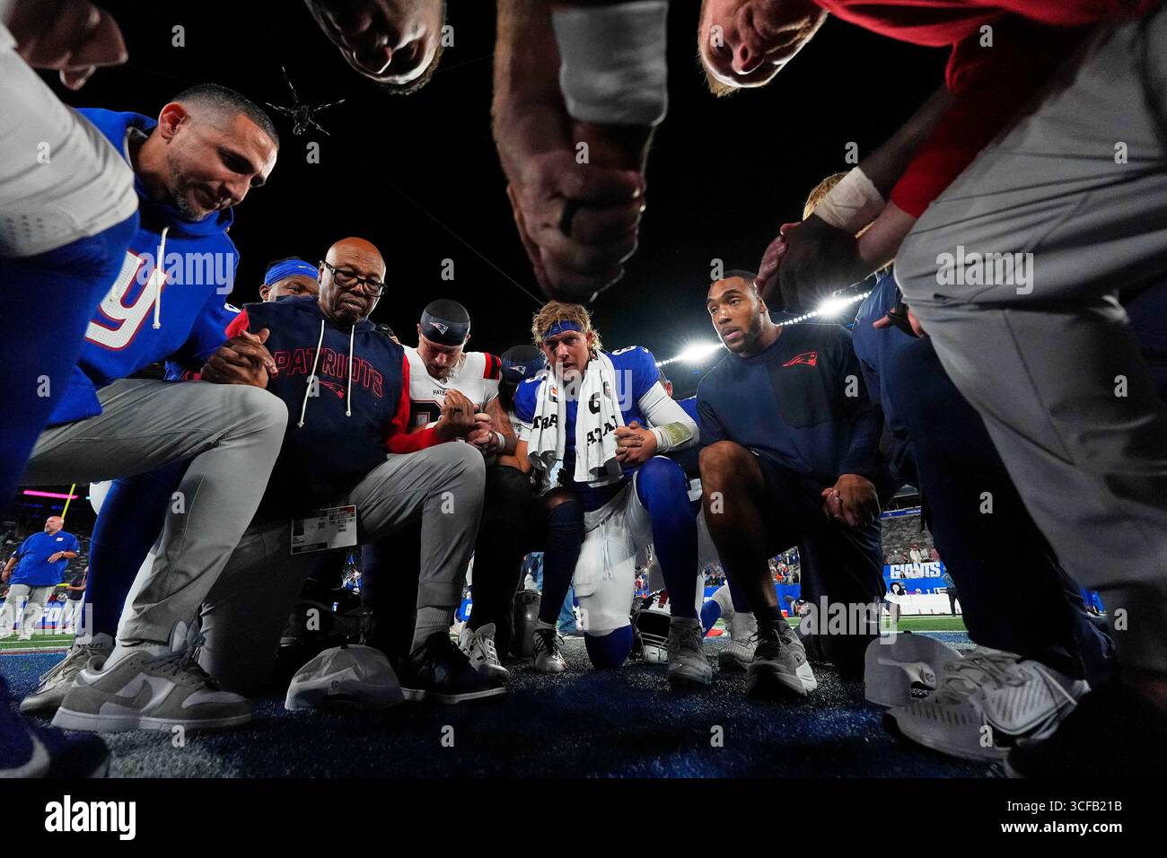 New York Giants and New England Patriots players gather for prayer on ...