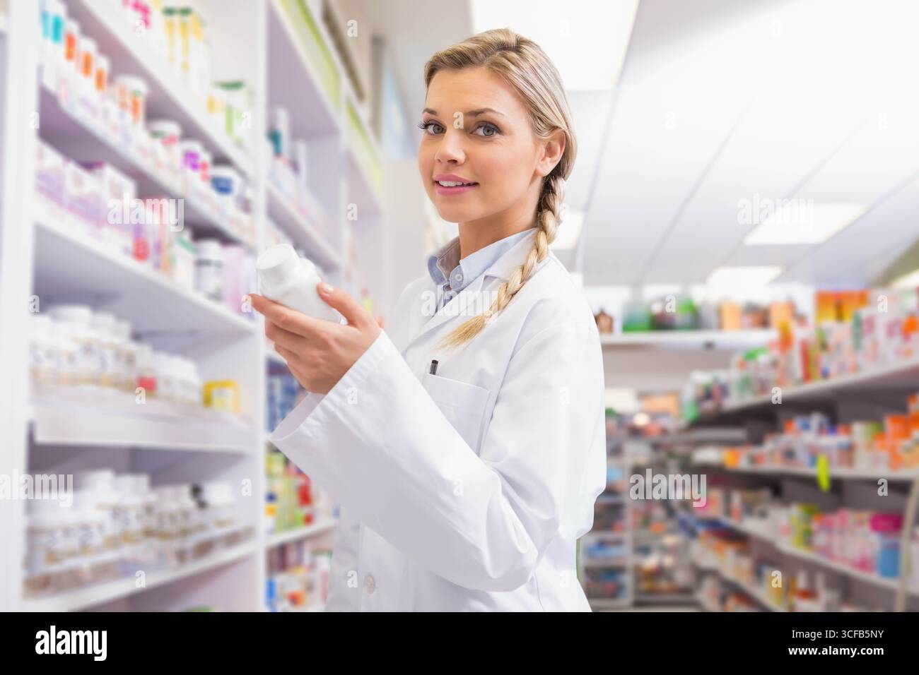 Female pharmacist wearing white lab coat in pharmacy aisle checking ...