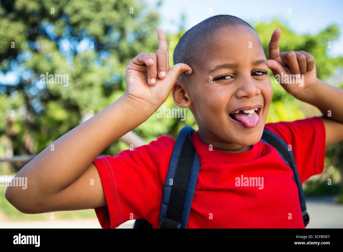 African American boy wearing red t-shirt making silly antler face ...