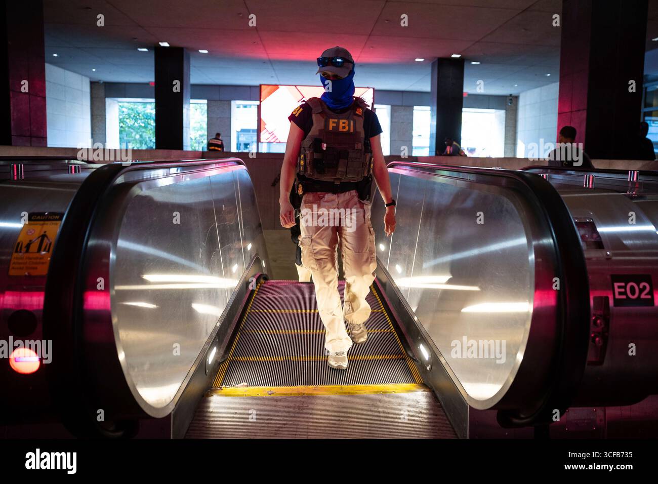 A masked Federal Bureau of Investigation (FBI) agent exits the L'Enfant ...