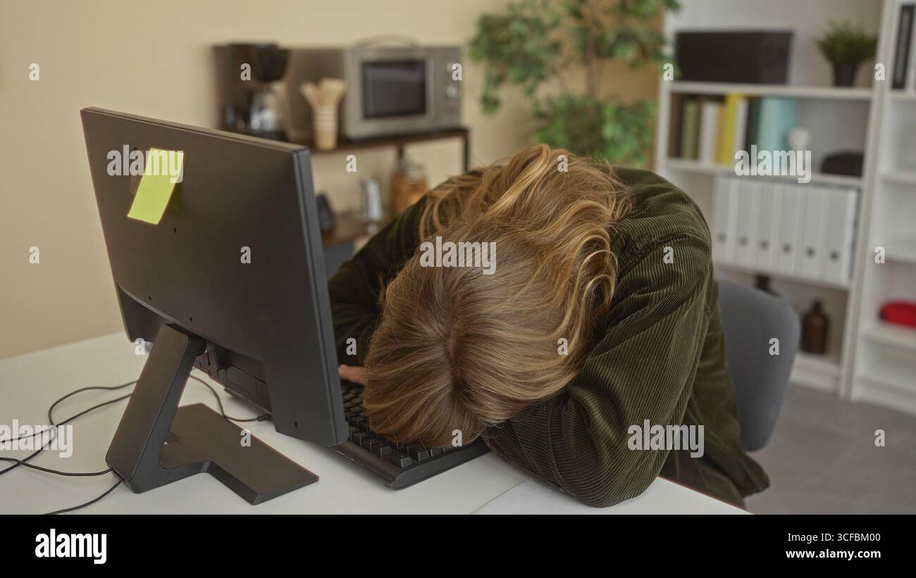 Blond man with long hair typing on a desktop keyboard while staring at ...