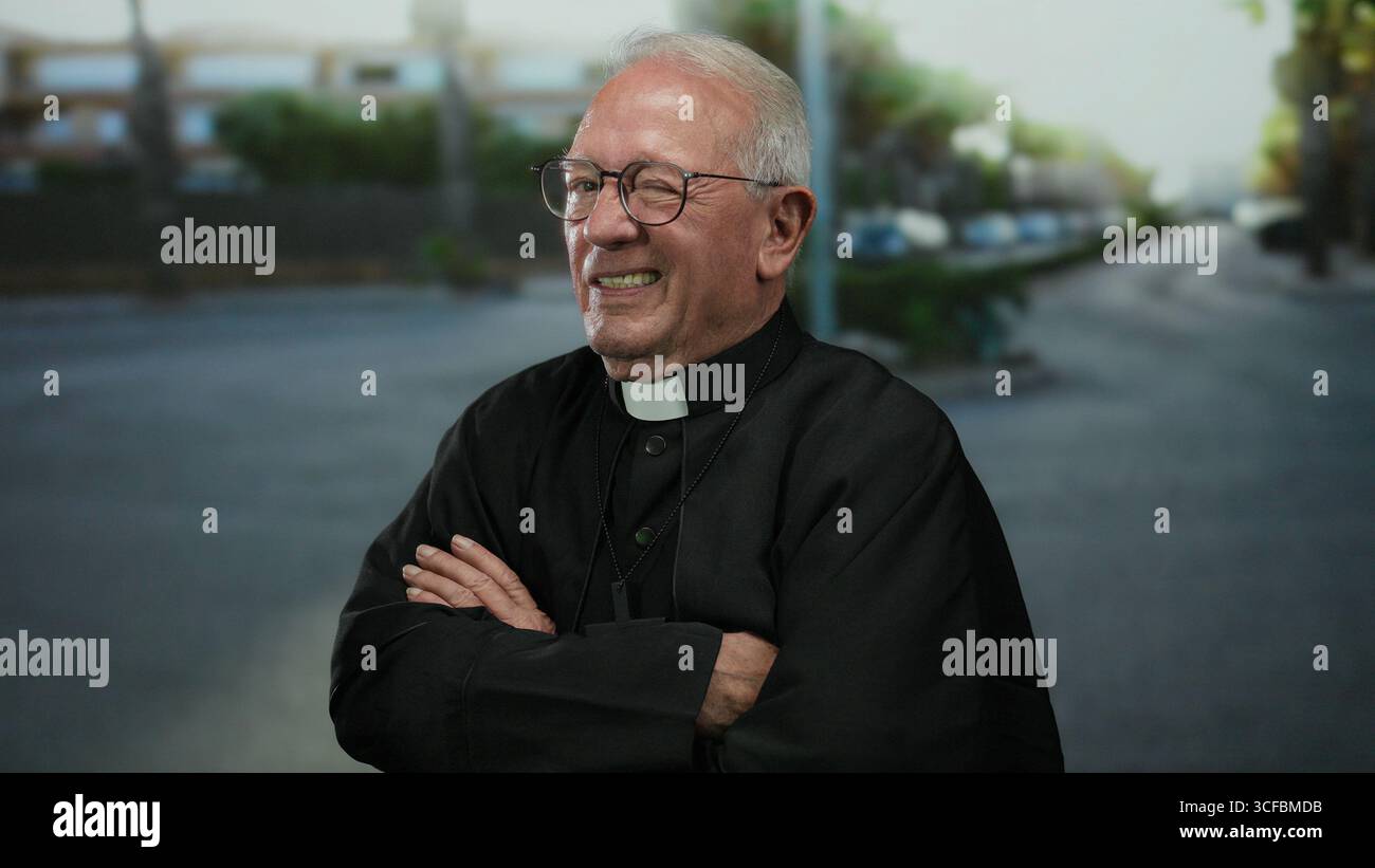 Elderly priest standing outdoors on street wearing black clerical ...