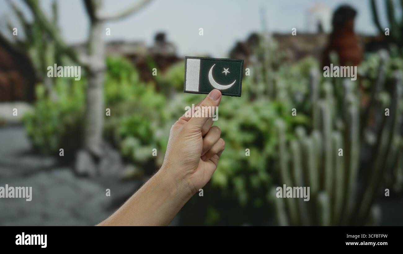 Hand displaying embroidered pakistani flag patch in outdoor park ...