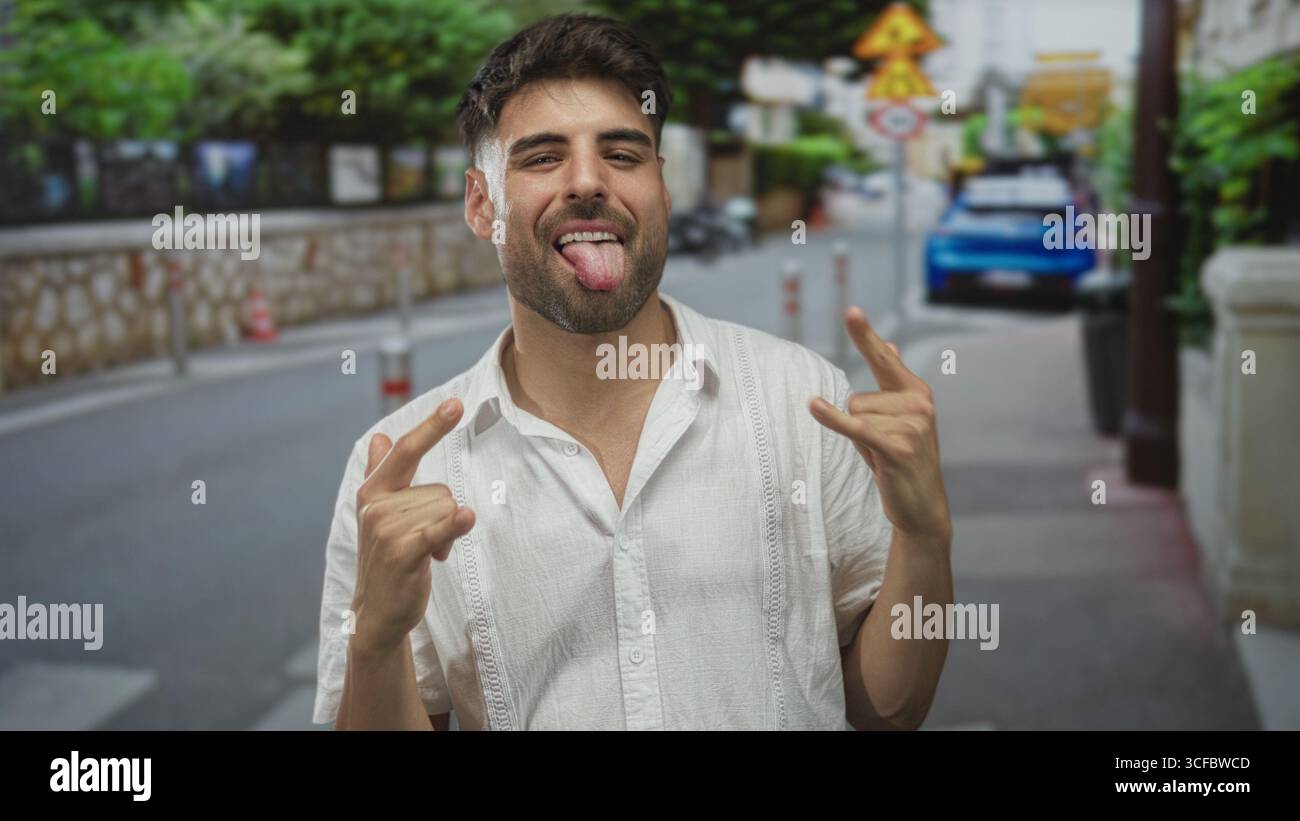 Man grinning and showing tongue while making rock horns gesture with ...