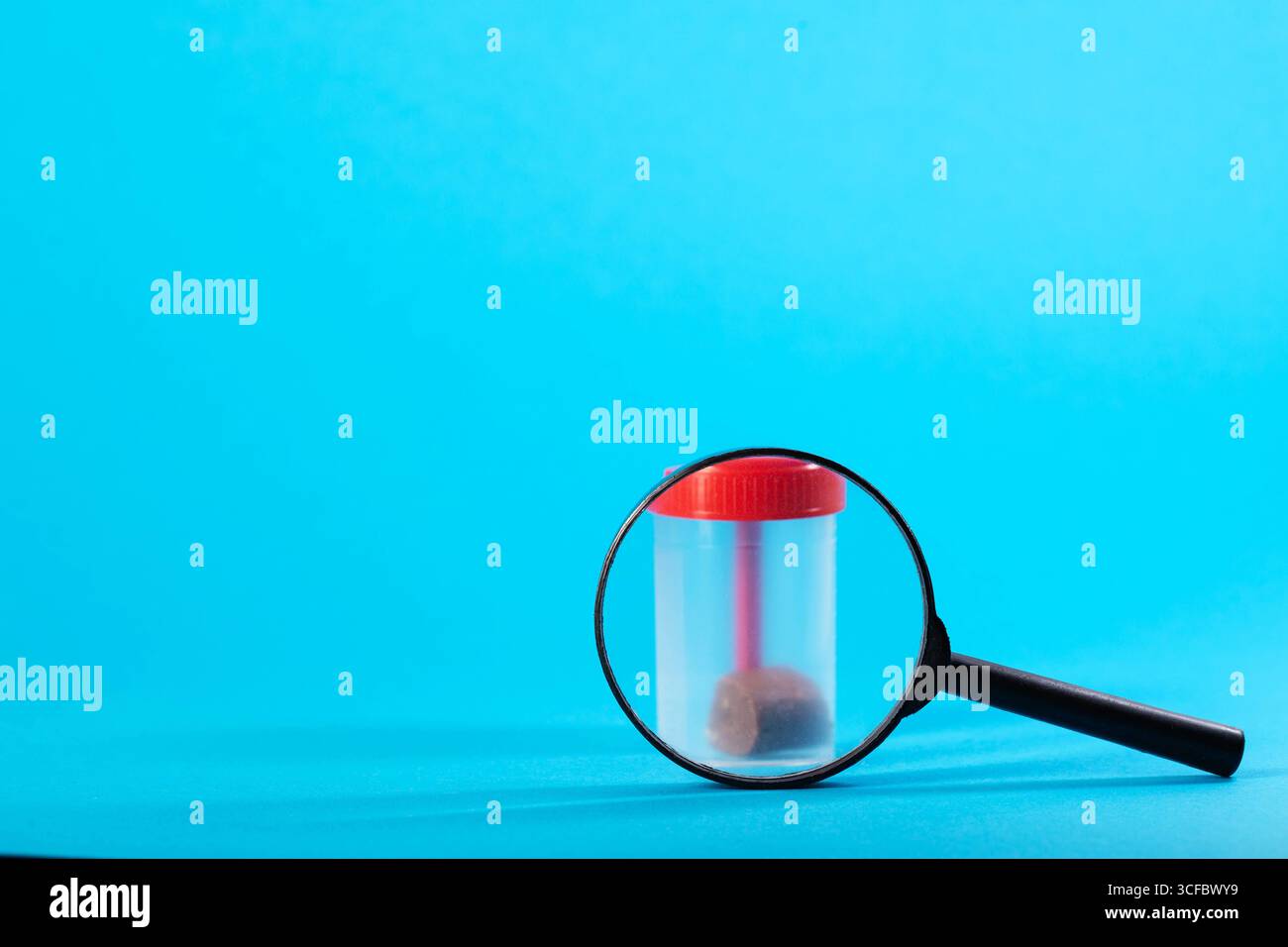 Magnifying glass with stool analysis container on a blue background ...