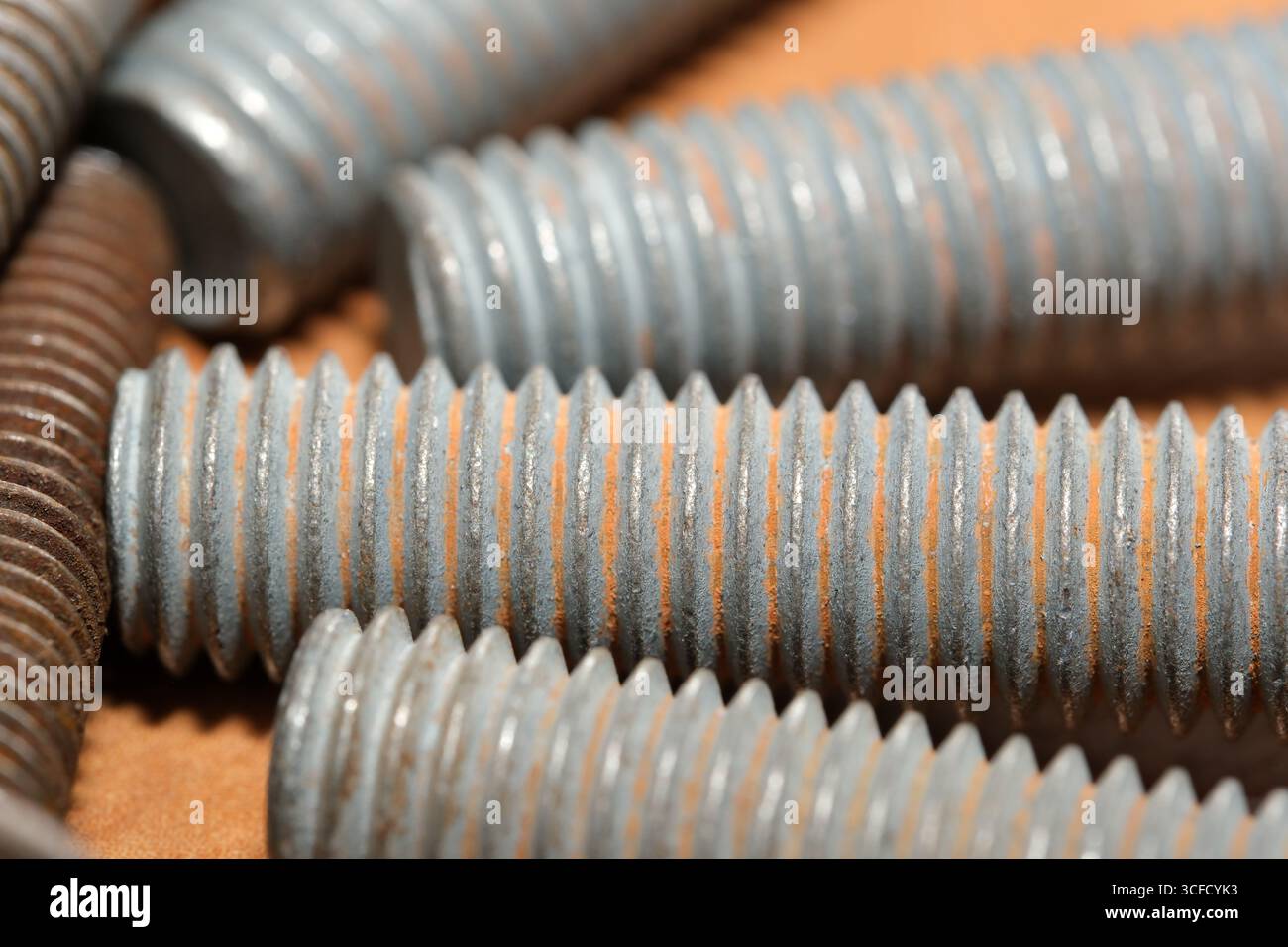 Metallic bolts rest on a surface, highlighting their intricate threaded ...