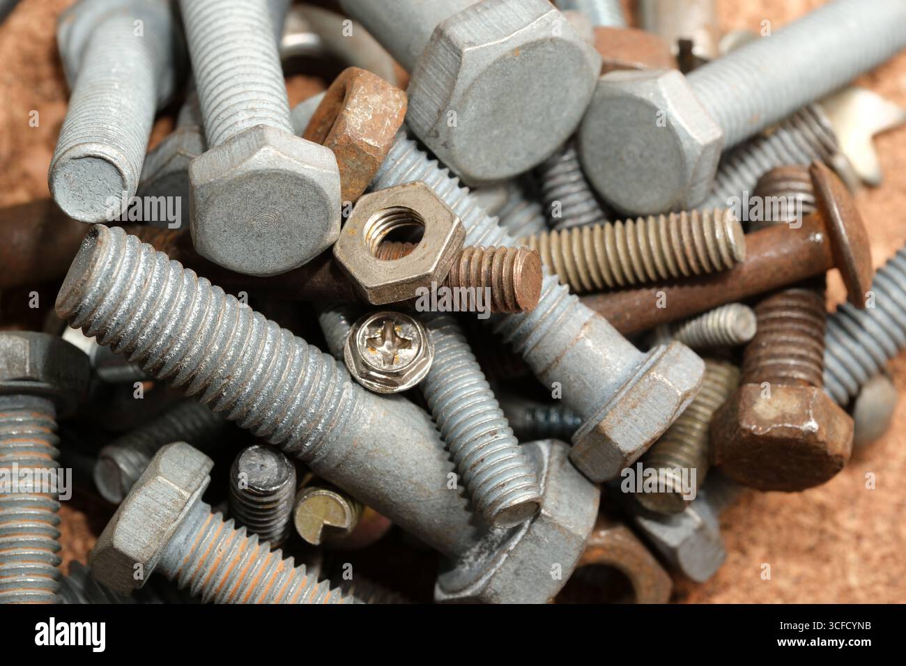 Various screws, bolts, and nuts clutter a workbench in a busy workshop ...