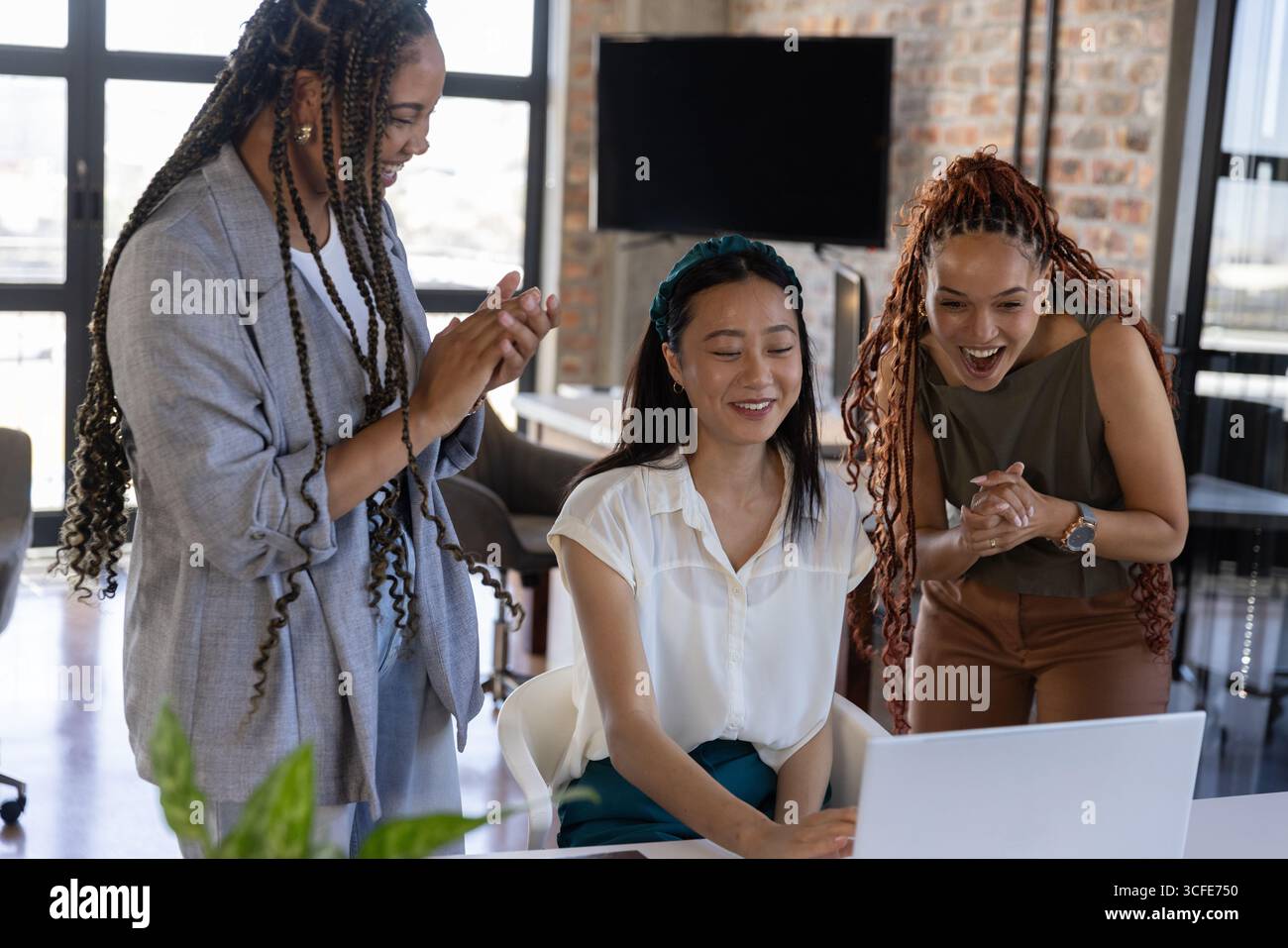 Diverse female coworkers in smart attire celebrating project success ...