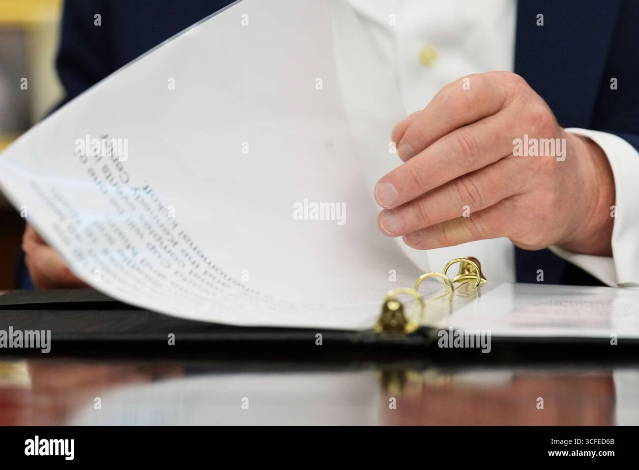 President Donald Trump looks at papers in the Oval Office of the White ...