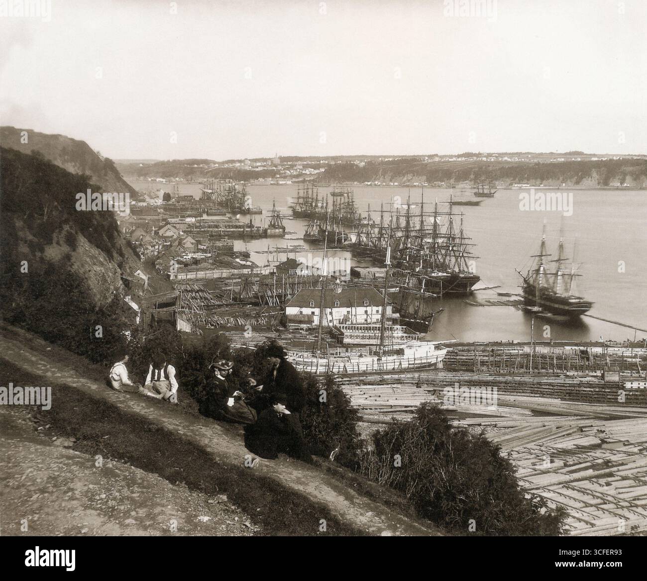 A group of people sitting on a hill overlooking the shipyard in Quebec ...