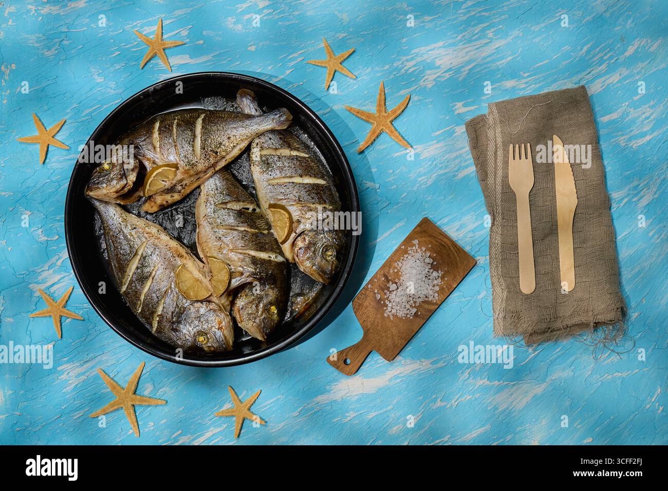 Fresh dorado fish prepared with lemon slices on a blue beach-themed ...