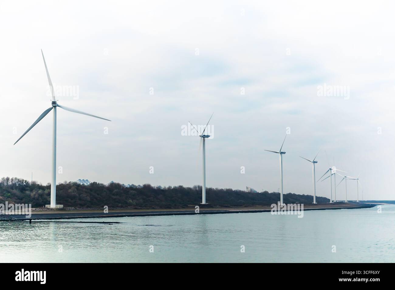Wind farms onshore along a water channel in the Netherlands. Wind ...