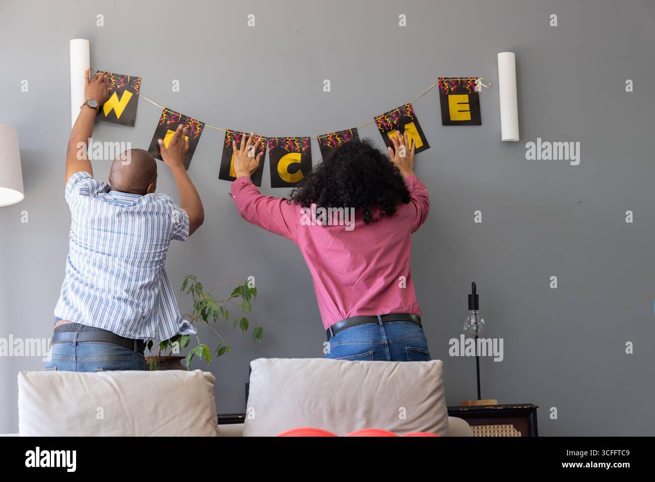 Couple hanging string black cards spelling welcome in yellow on living ...