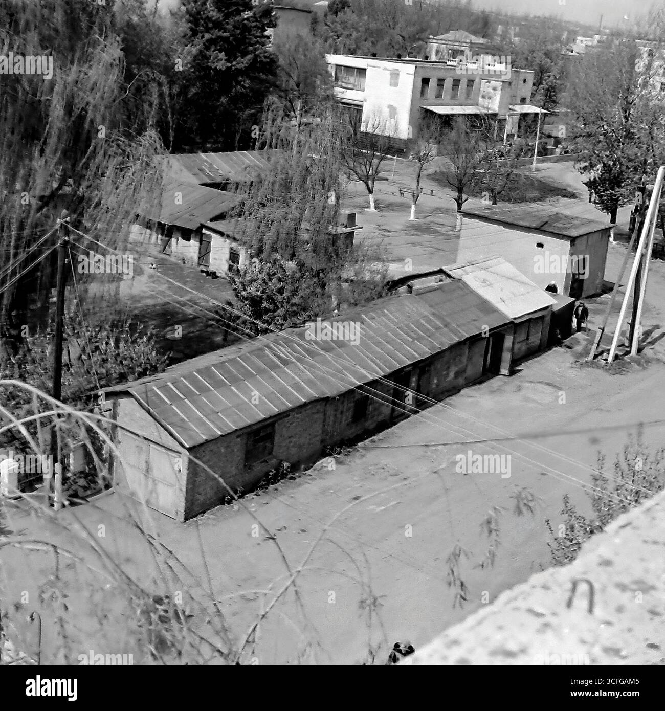 An unceremonial view of the backyard and utility buildings of the ...