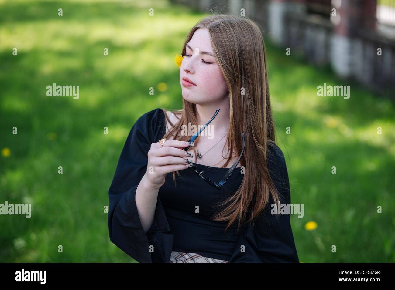 High school student relaxing in a park during spring break, holding ...