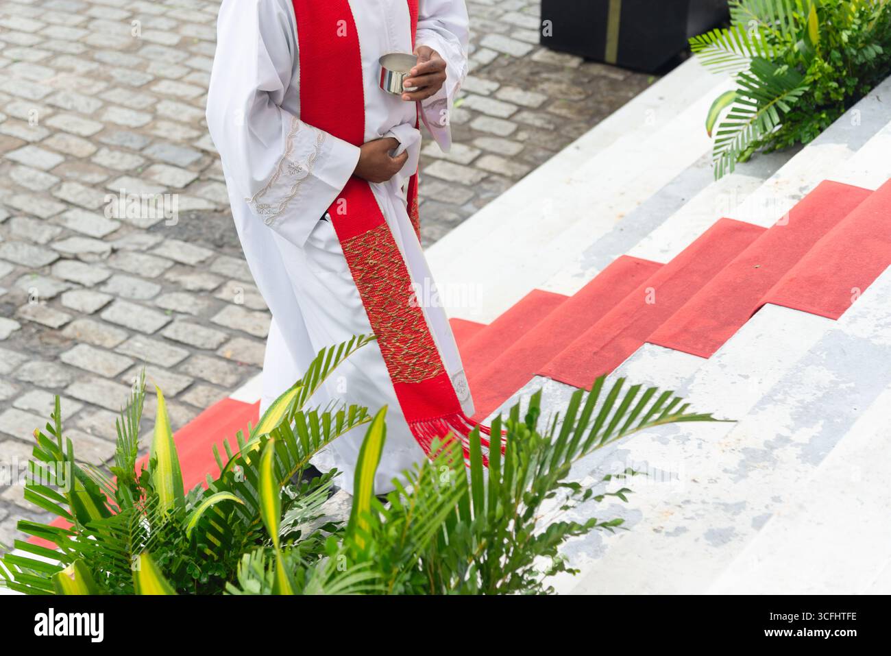 Priest dressed in character walking up a staircase with a red carpet ...
