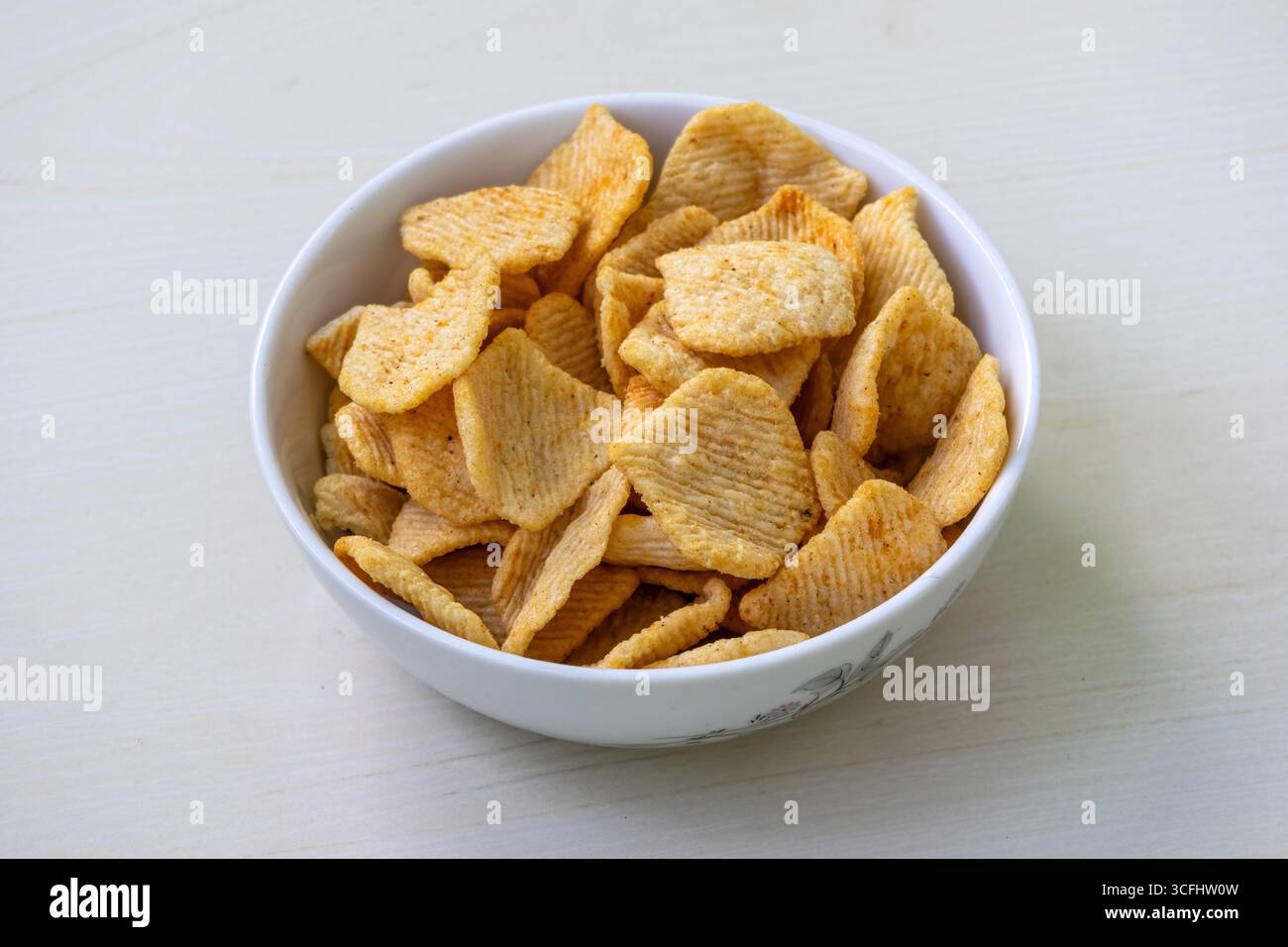 Crispy potato crackers chips in a white ceramic bowl on a light wooden ...