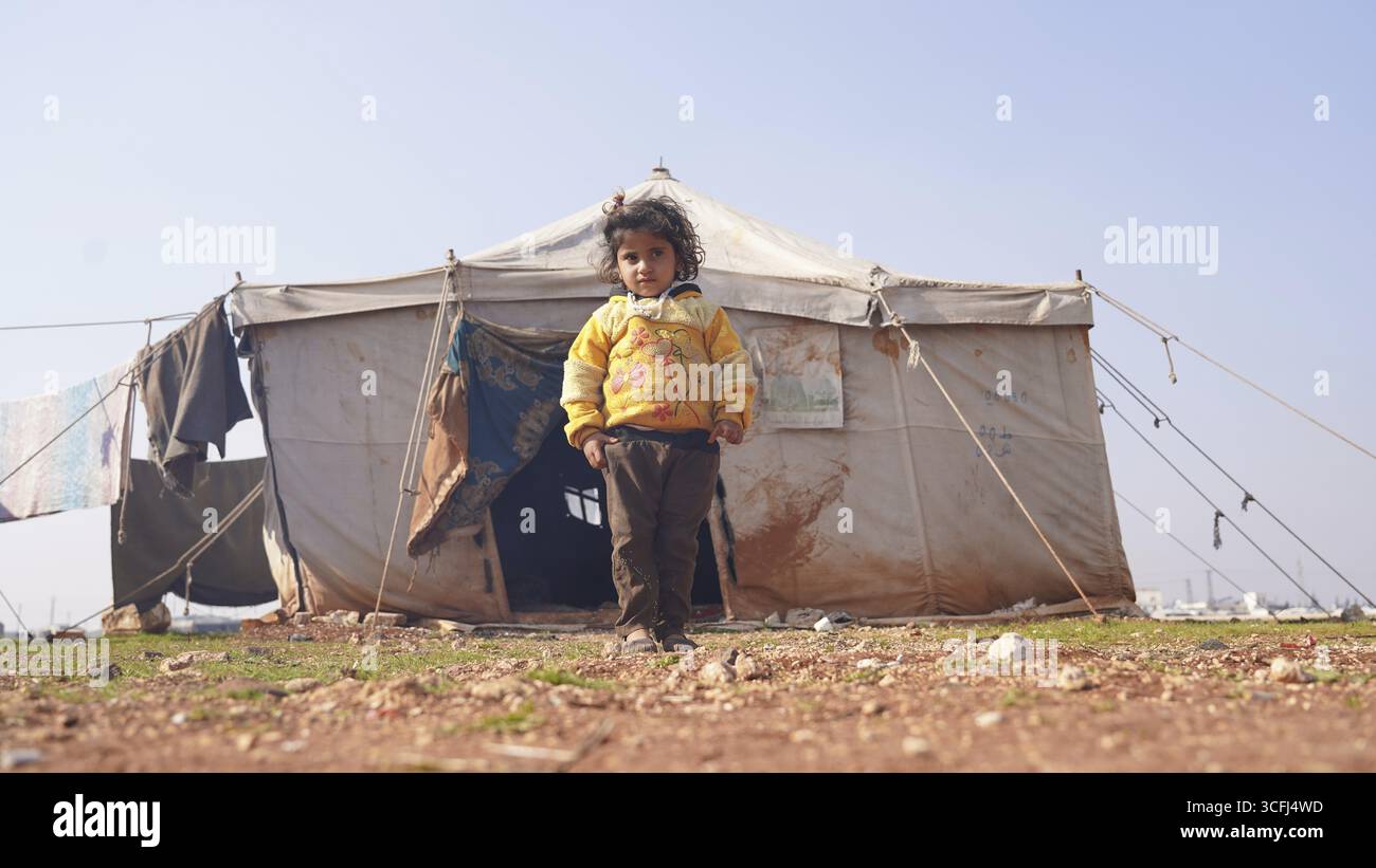 A Syrian girl stands in front of her tent in a refugee camp. World ...