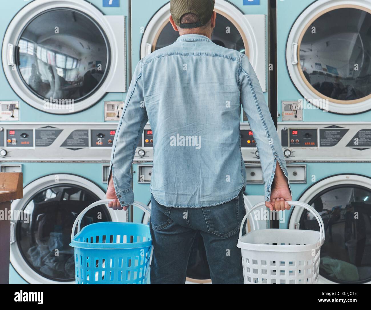 Customer holding laundry baskets while using clothes dryers in a public ...