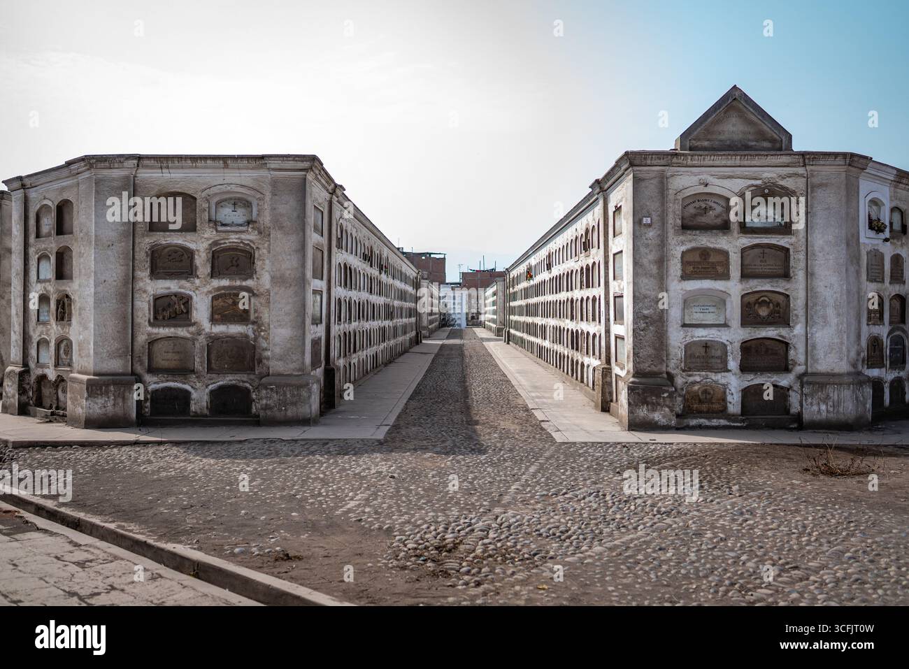 Symmetrical walkway between historic mausoleum walls filled with burial ...
