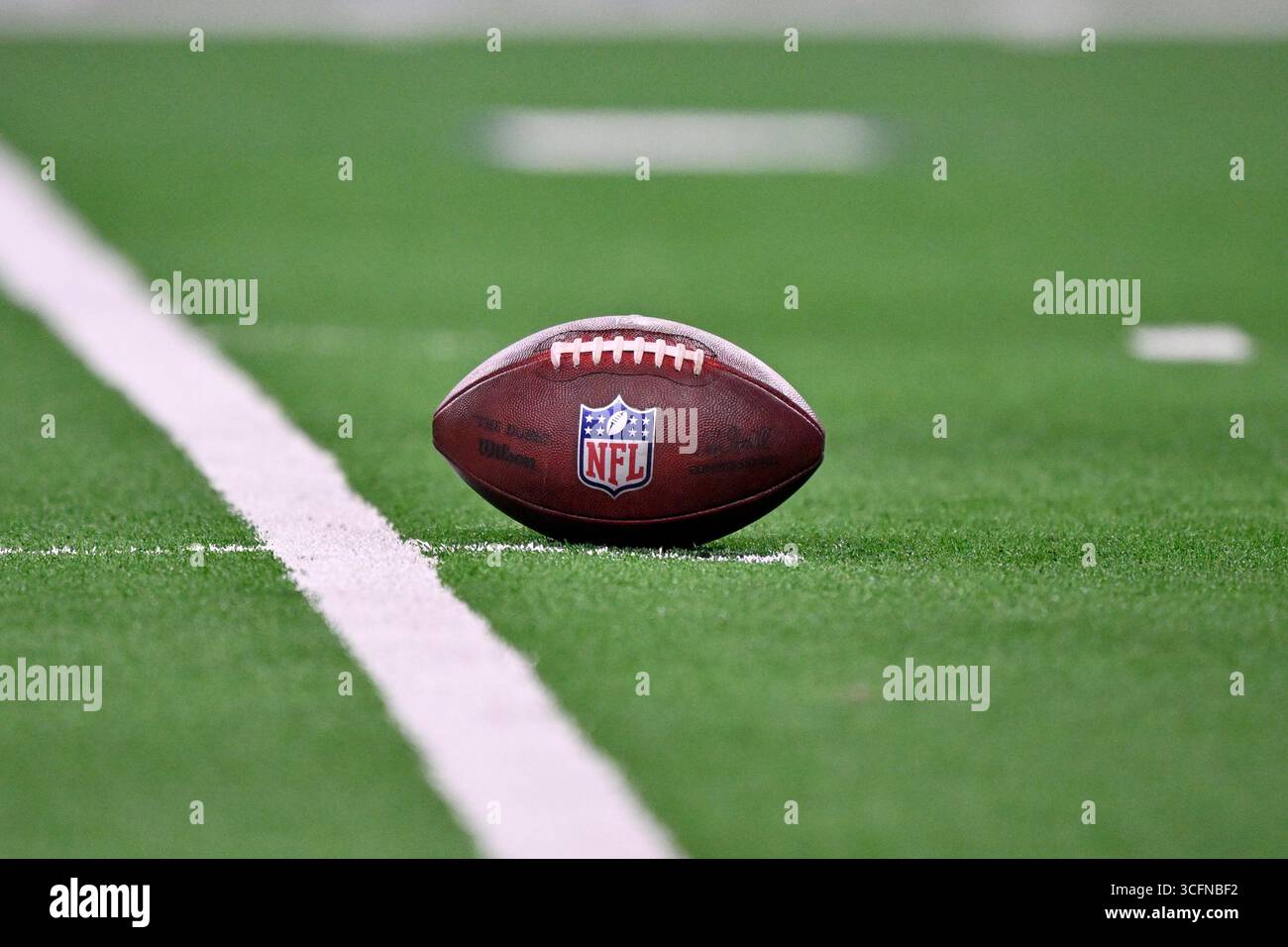 The NFL logo is seen on a football during a preseason NFL football game ...