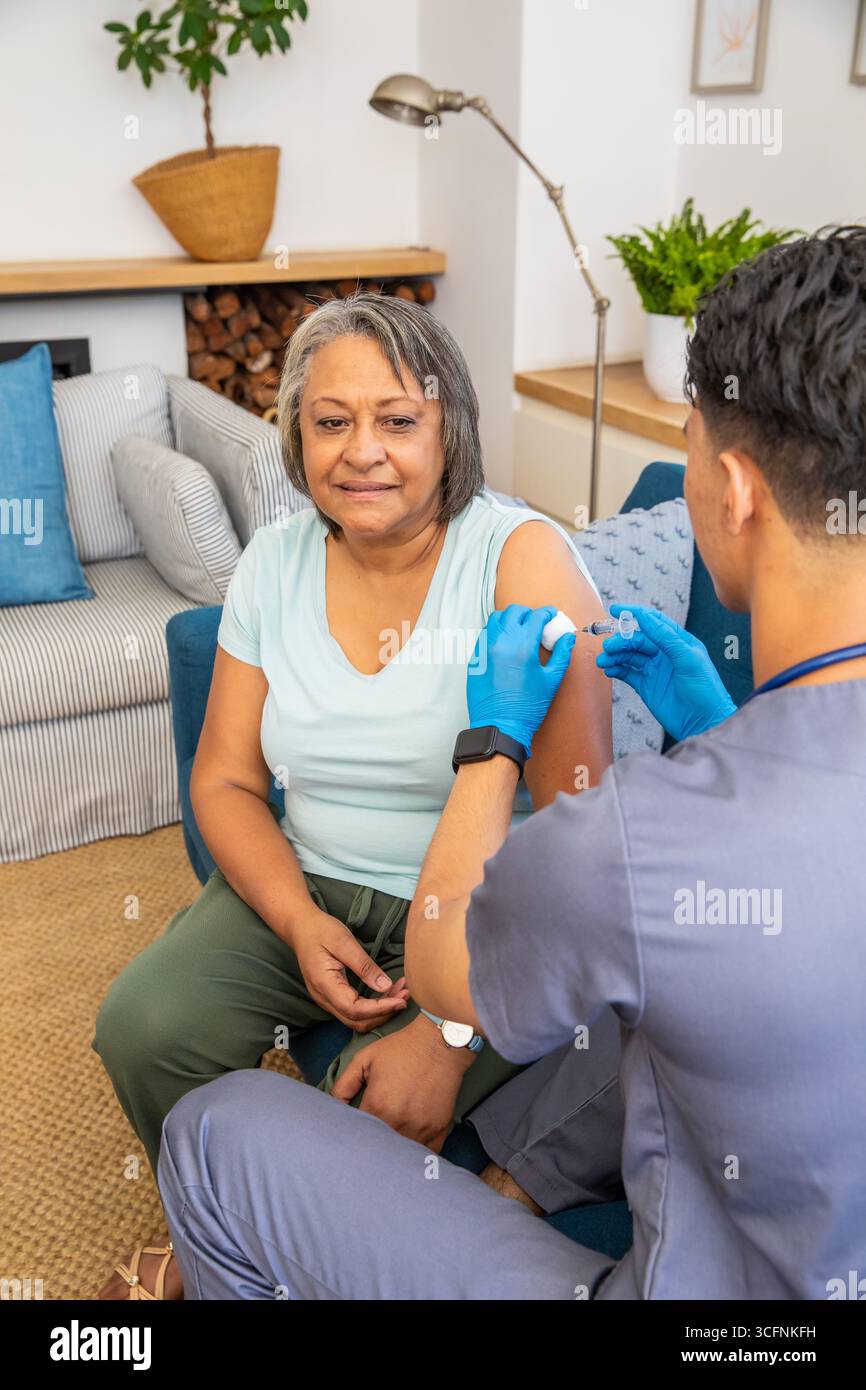 Senior hispanic woman receiving vaccine shot, male nurse giving ...