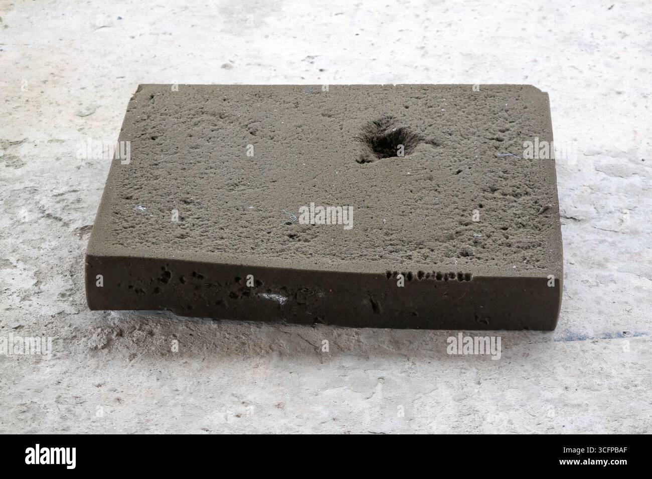An old, used piece of sponge foam sits on a concrete rooftop. Despite ...