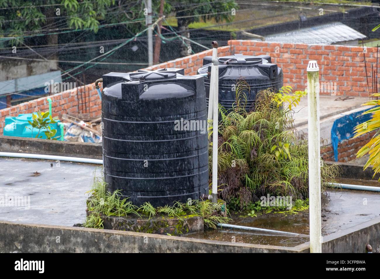 Black plastic water tanks on a residential building roof in Bangladesh ...
