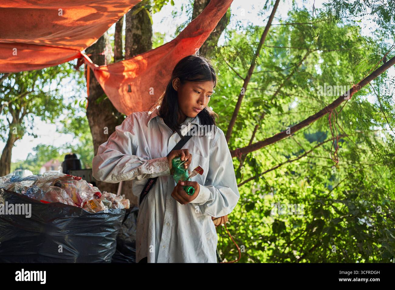 Isela Santiago Morales, who works with her family collecting PET bottles, sorts recyclables at ...