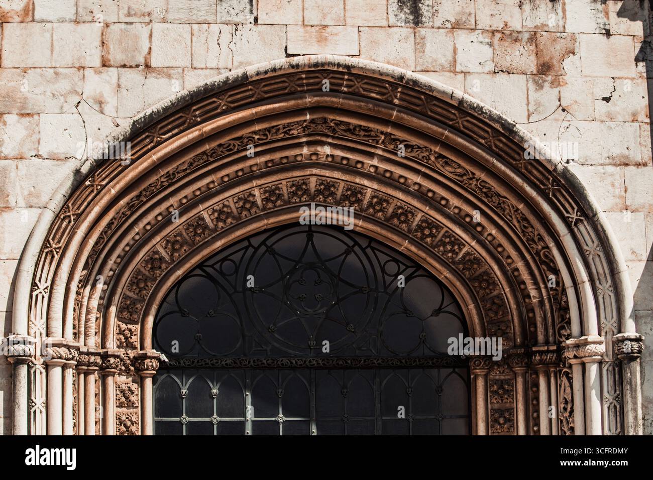 The image shows a detailed stone archway with an intricate window ...