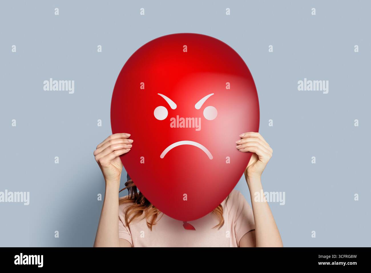 girl holding balloon with angry face isolated over grey background ...