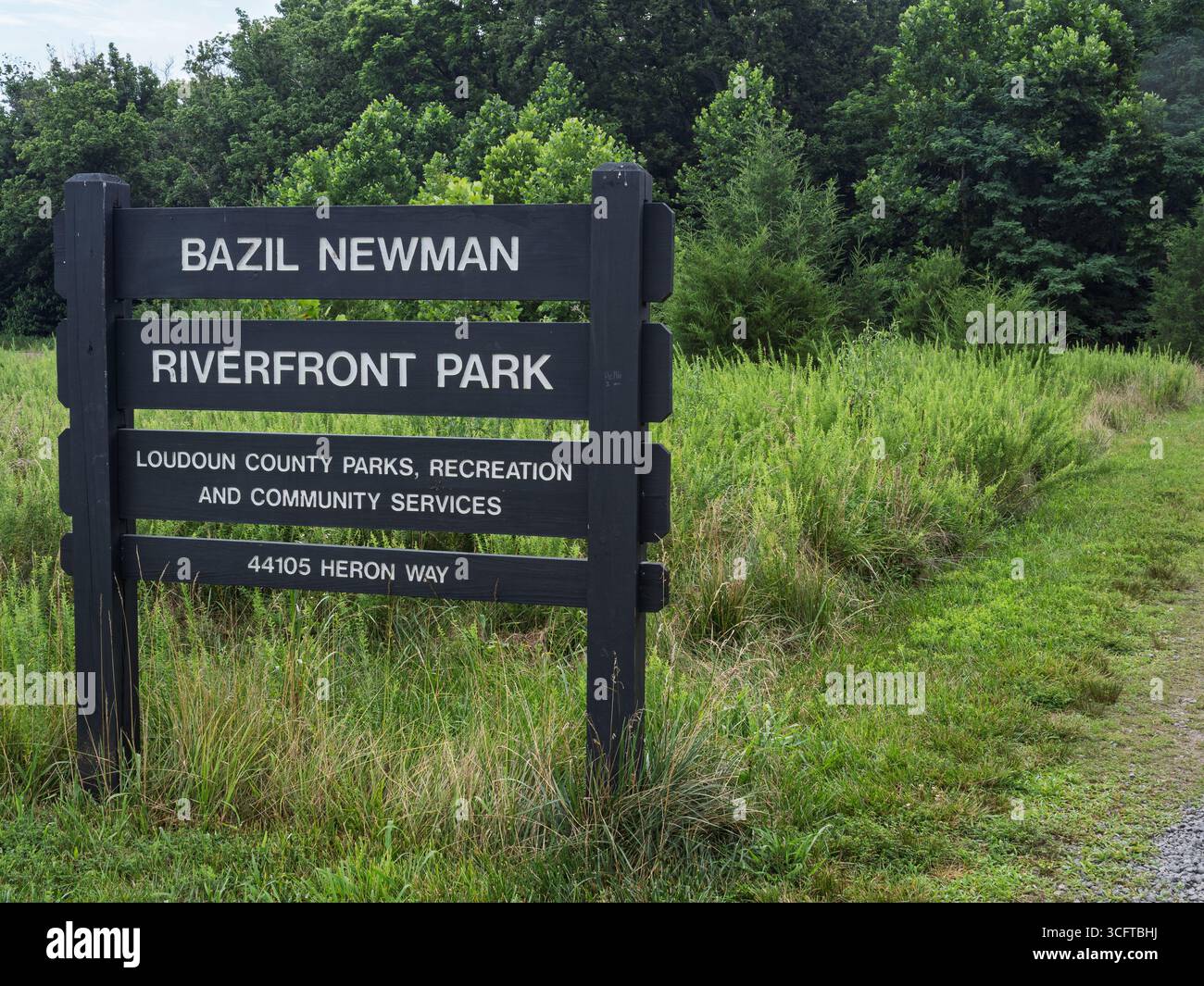 A close-up view of a wooden sign for Bazil Newman Riverfront Park ...