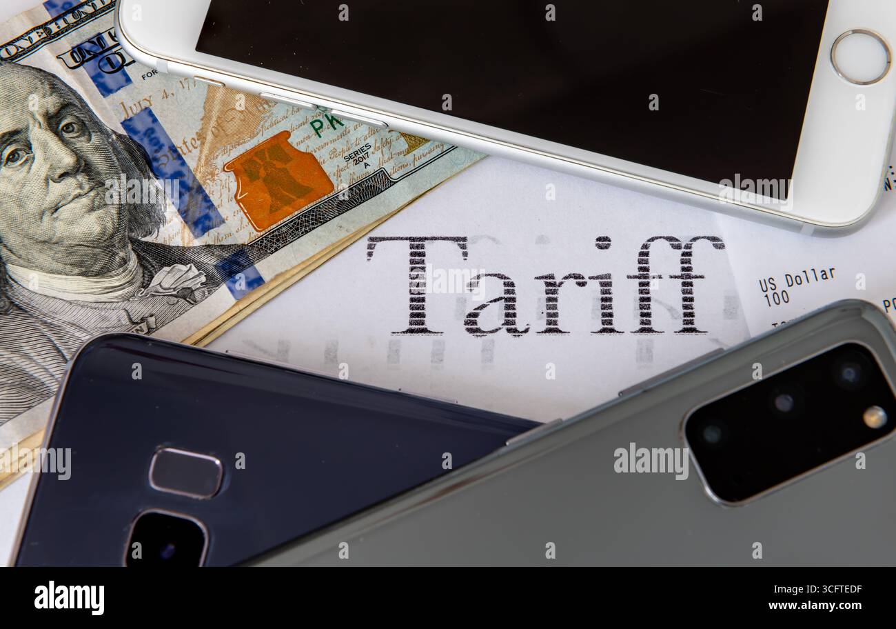 A stack of US Dollar bills and various mobile phones on the printed ...