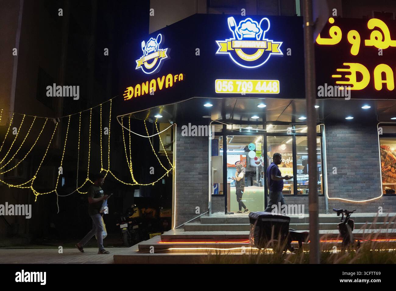Riyadh by night, Saudi Arabia Men walk with cellphones outside a ...