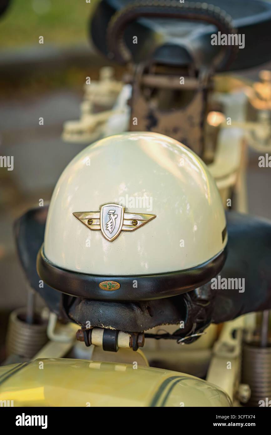 Close-up of vintage motorcycle helmet with emblem and golden accents on ...