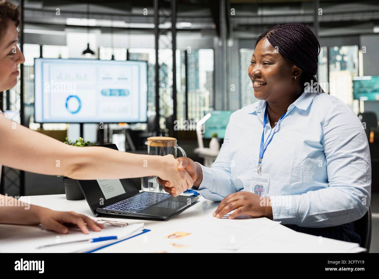 Black female candidate shaking hands with HR professional in corporate ...