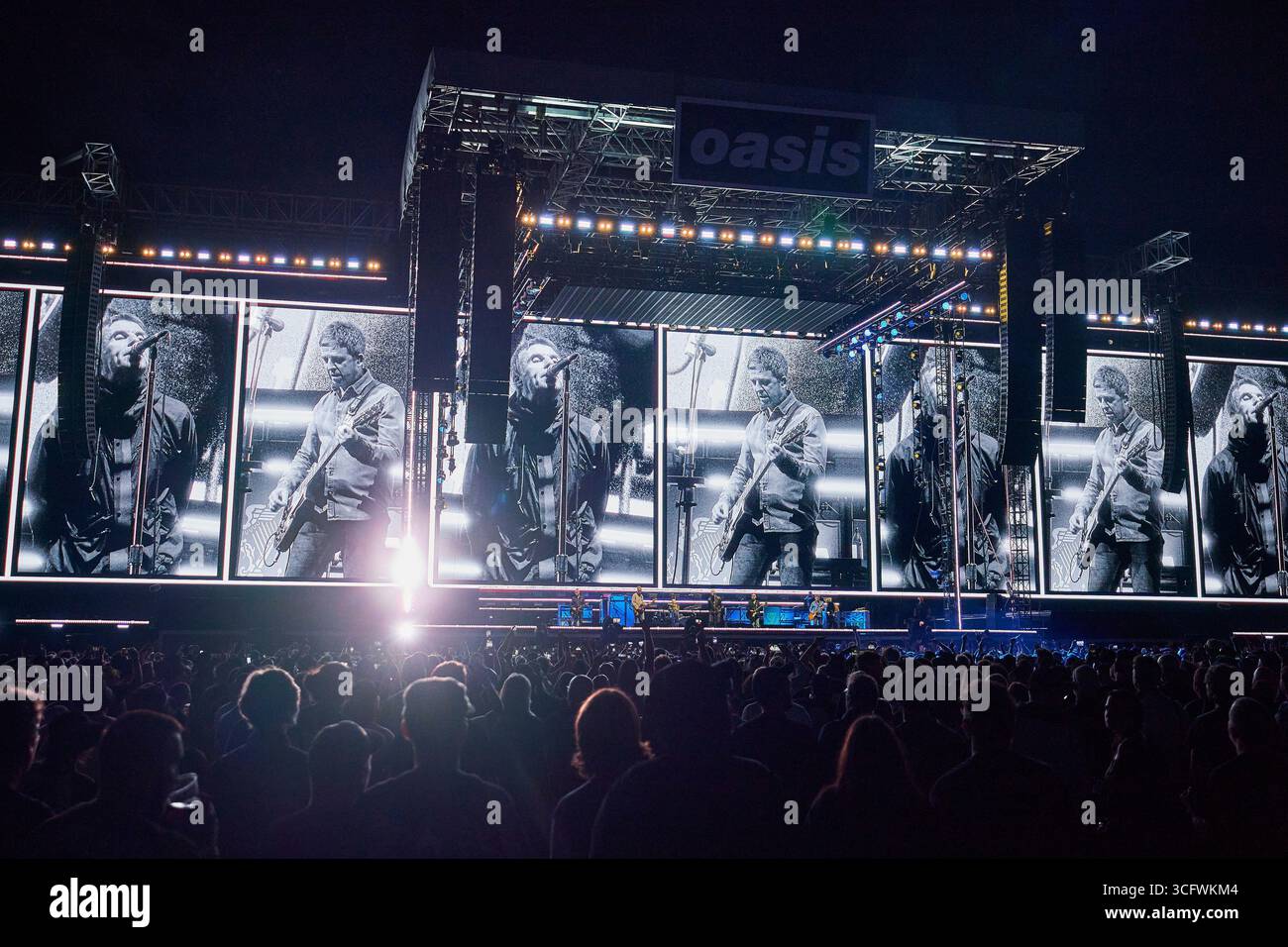 Liam Gallagher and Noel Gallagher of Oasis are shown on video screens ...