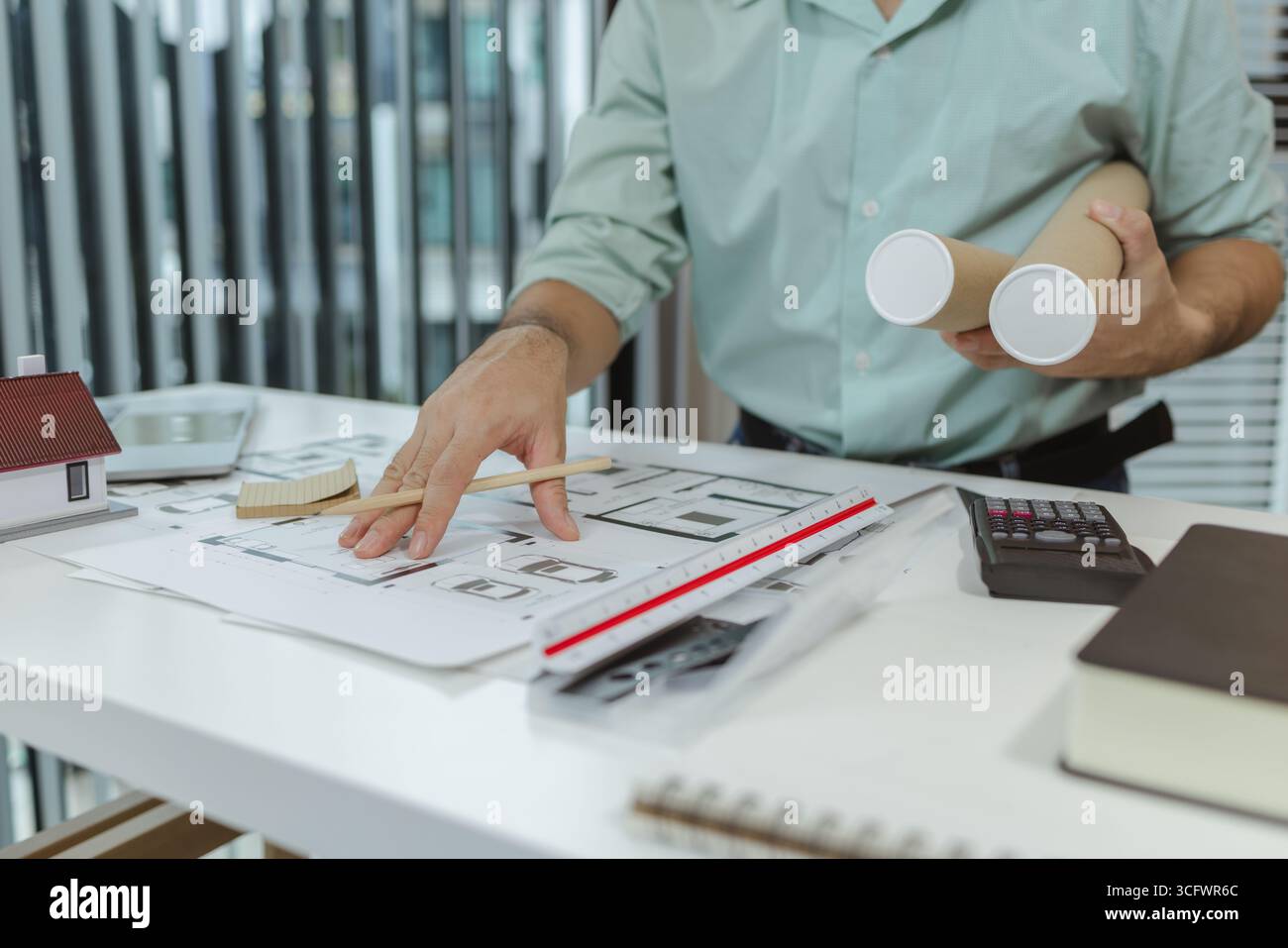 An architect pointing at house floor plans with a pencil while holding ...