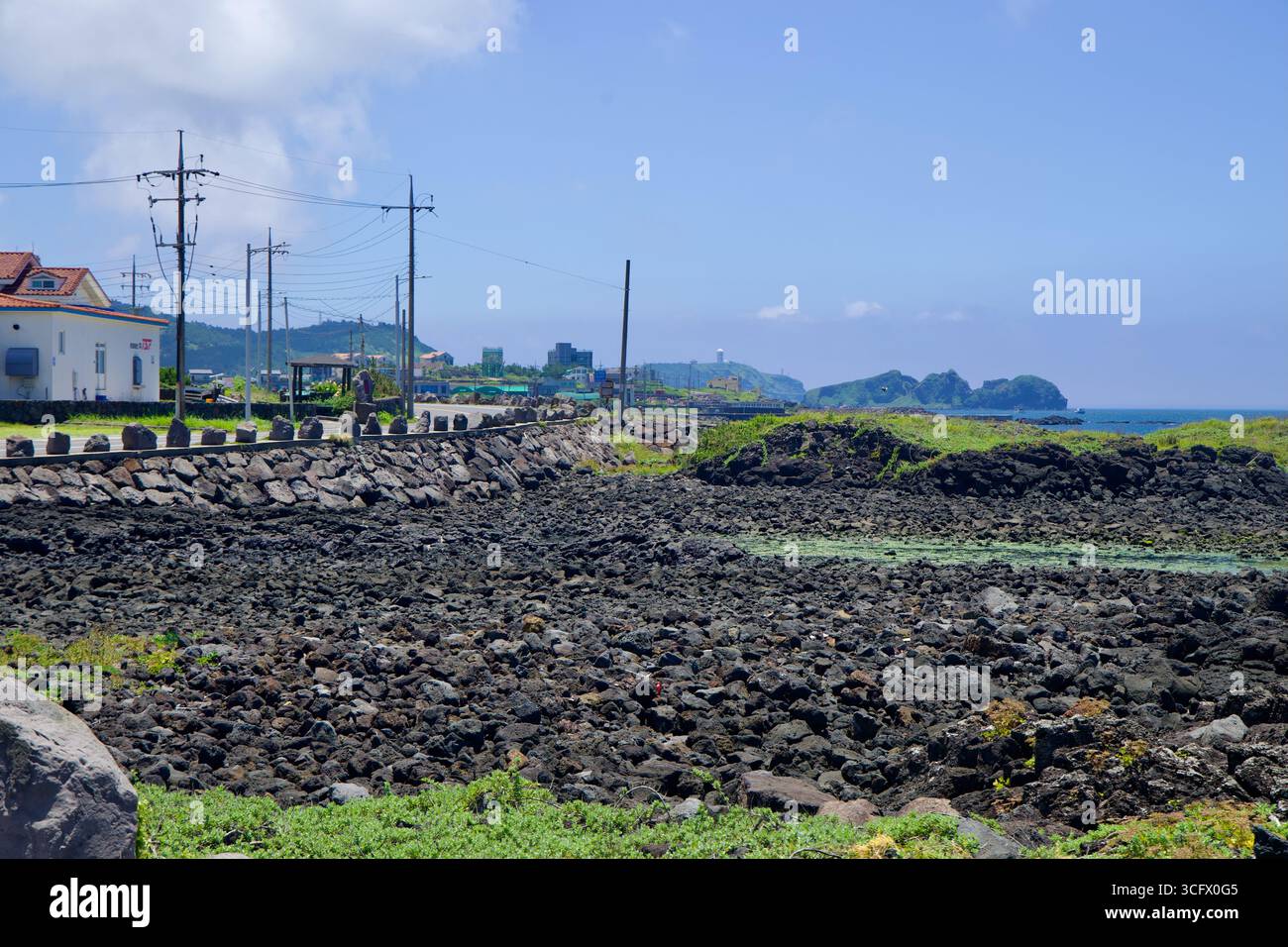 A low seawall and bike lane curve along the basalt shore near Yongsu on ...