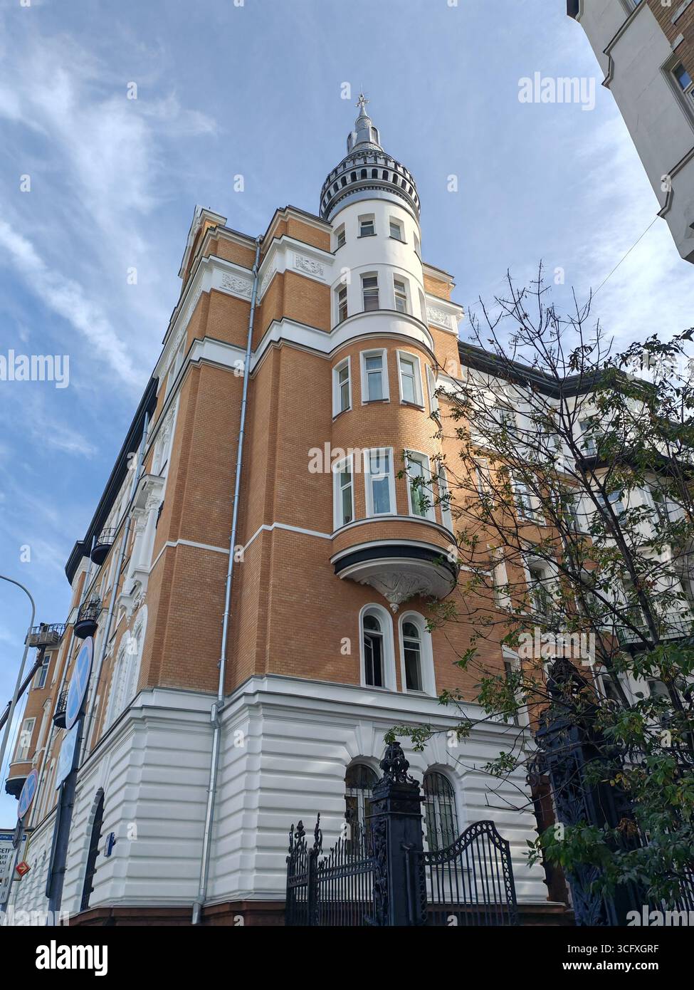 A historic brick building with a rounded tower and ornate spire against ...