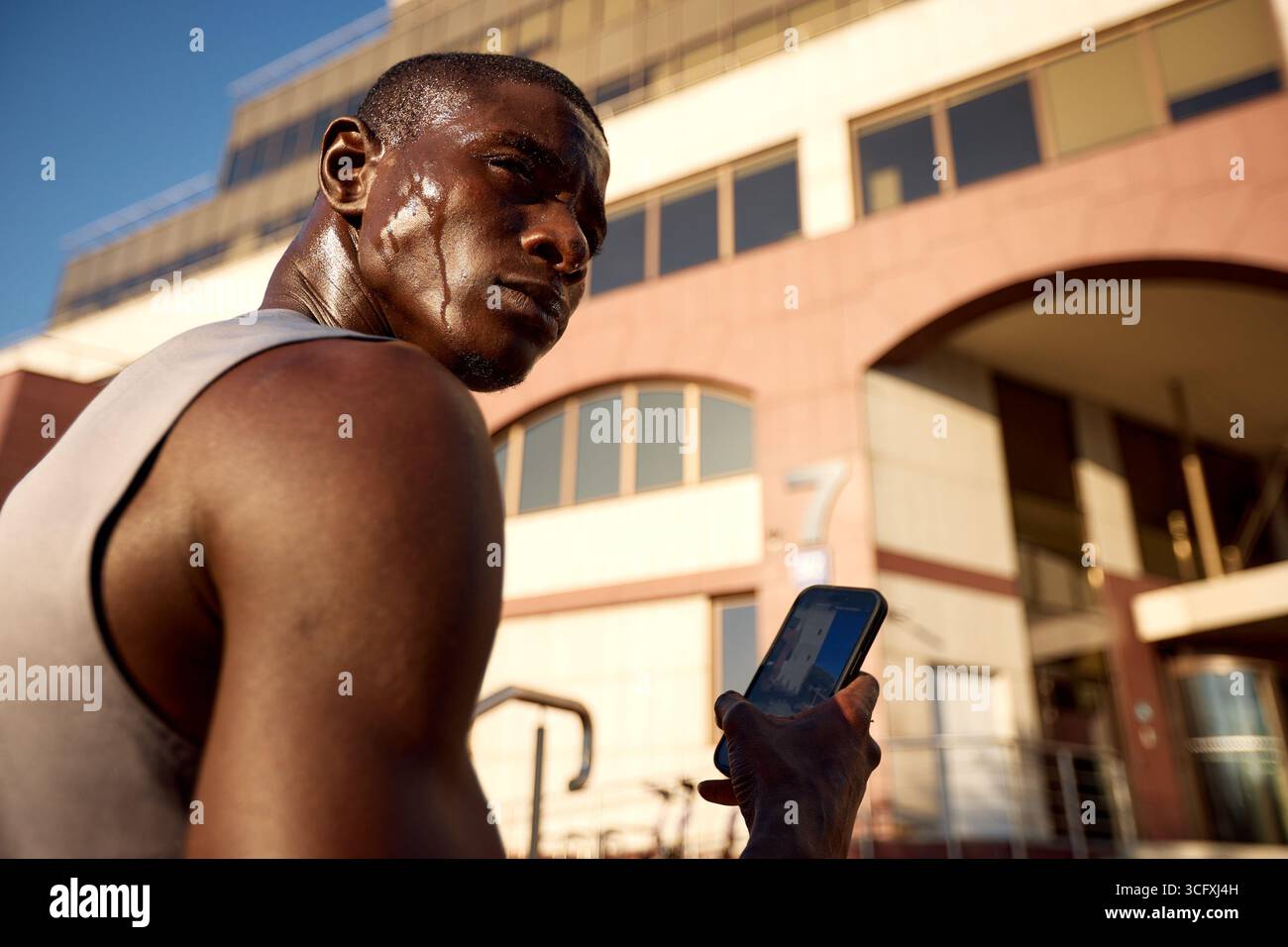 An athletic individual holding a smartphone outside near modern ...