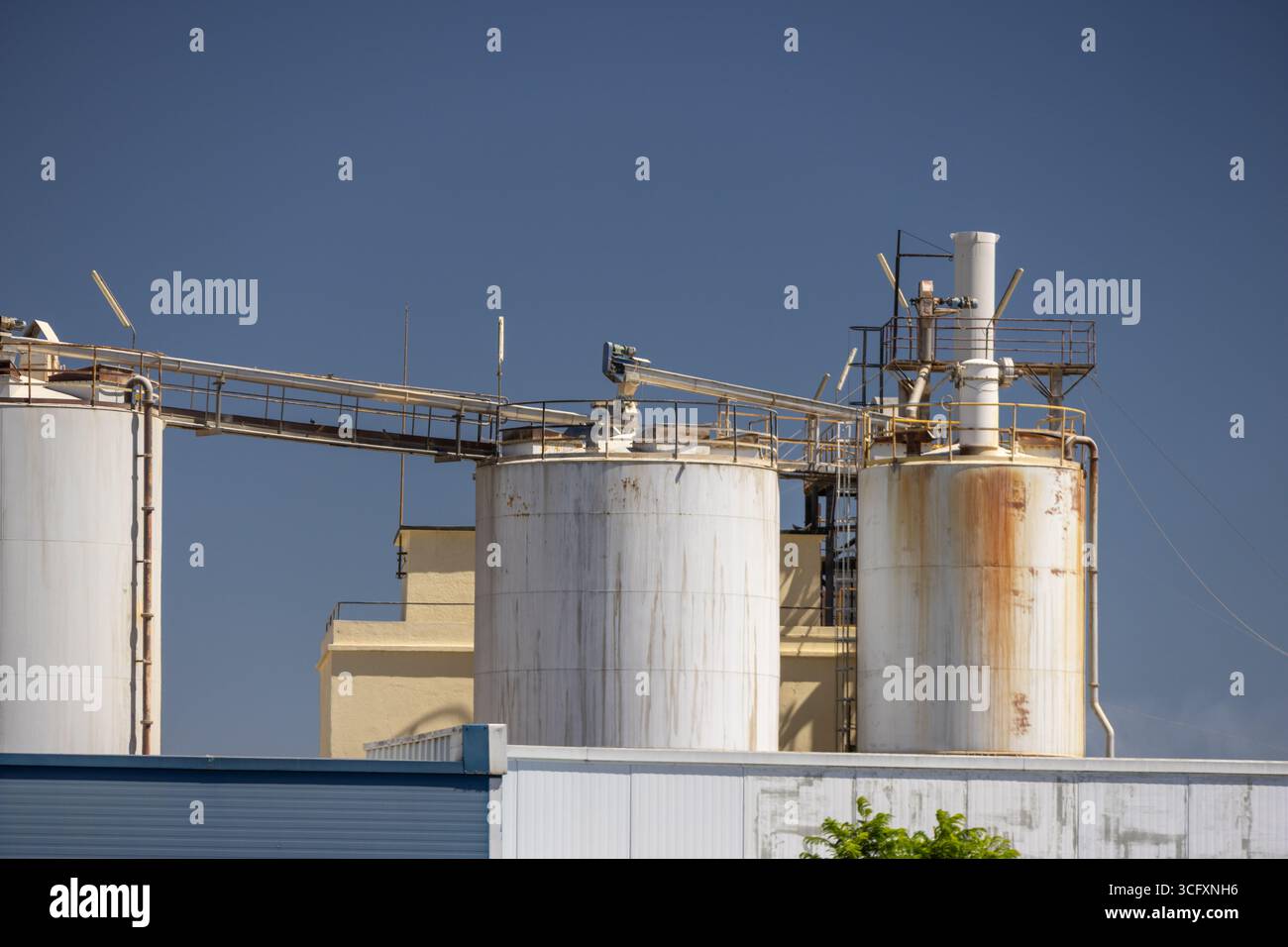 Large industrial silos and connecting pipes stand tall against a clear ...