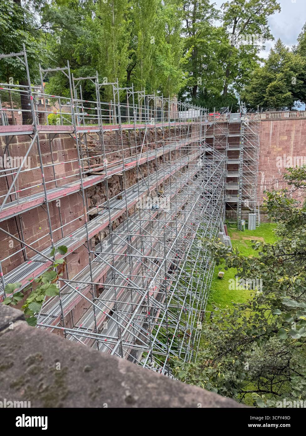 Extensive scaffolding installed along an ancient brick wall surrounded ...