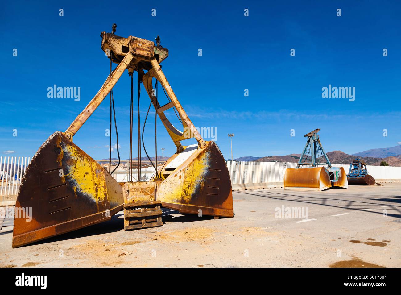 Large cargo buckets stand on the territory of the seaport for unloading and unloading bulk cargo ...