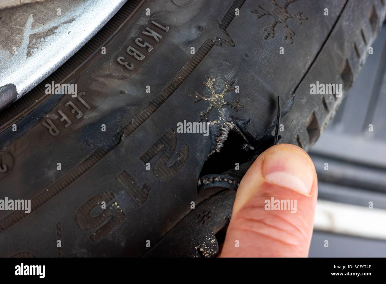 Car tire torn apart after riding on sharp road obstacles. Big hole on ...