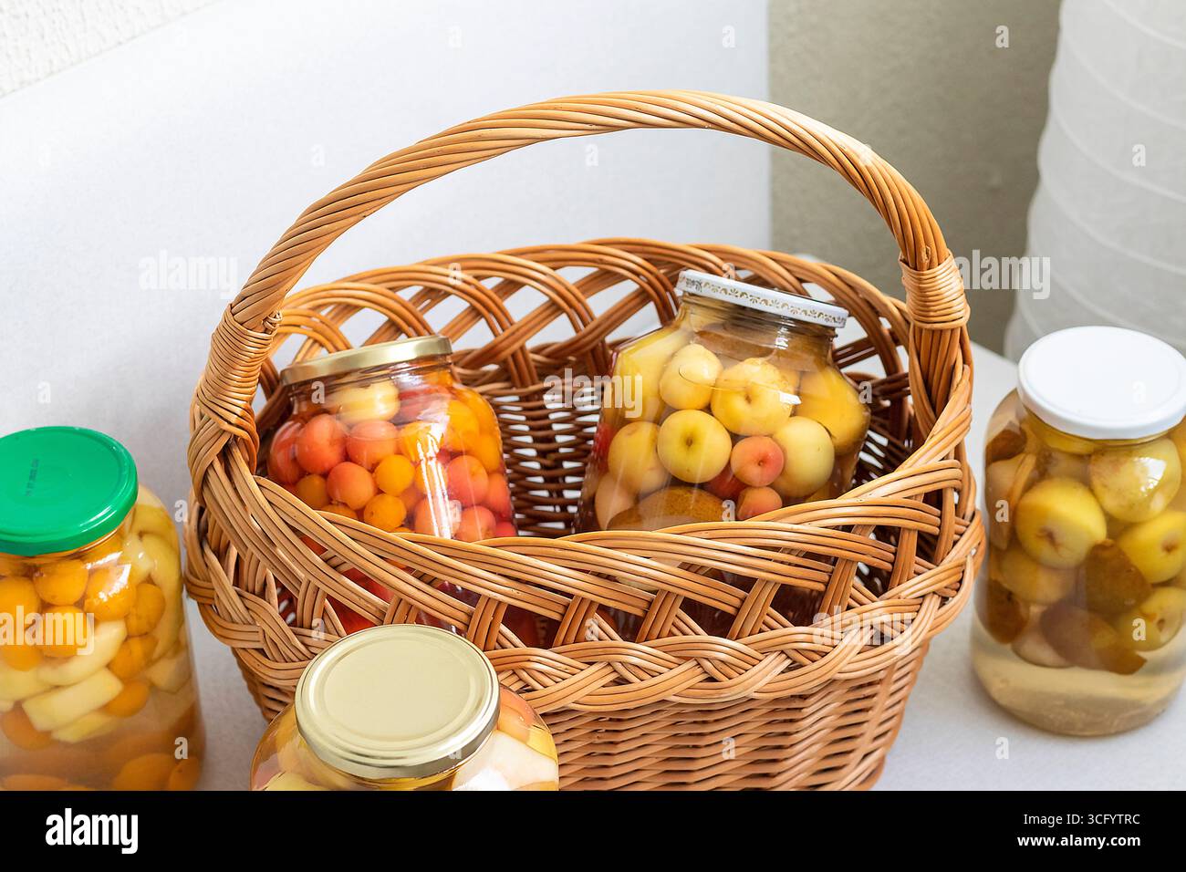 Canned compote in jars of various fruits and berries in the wicker ...