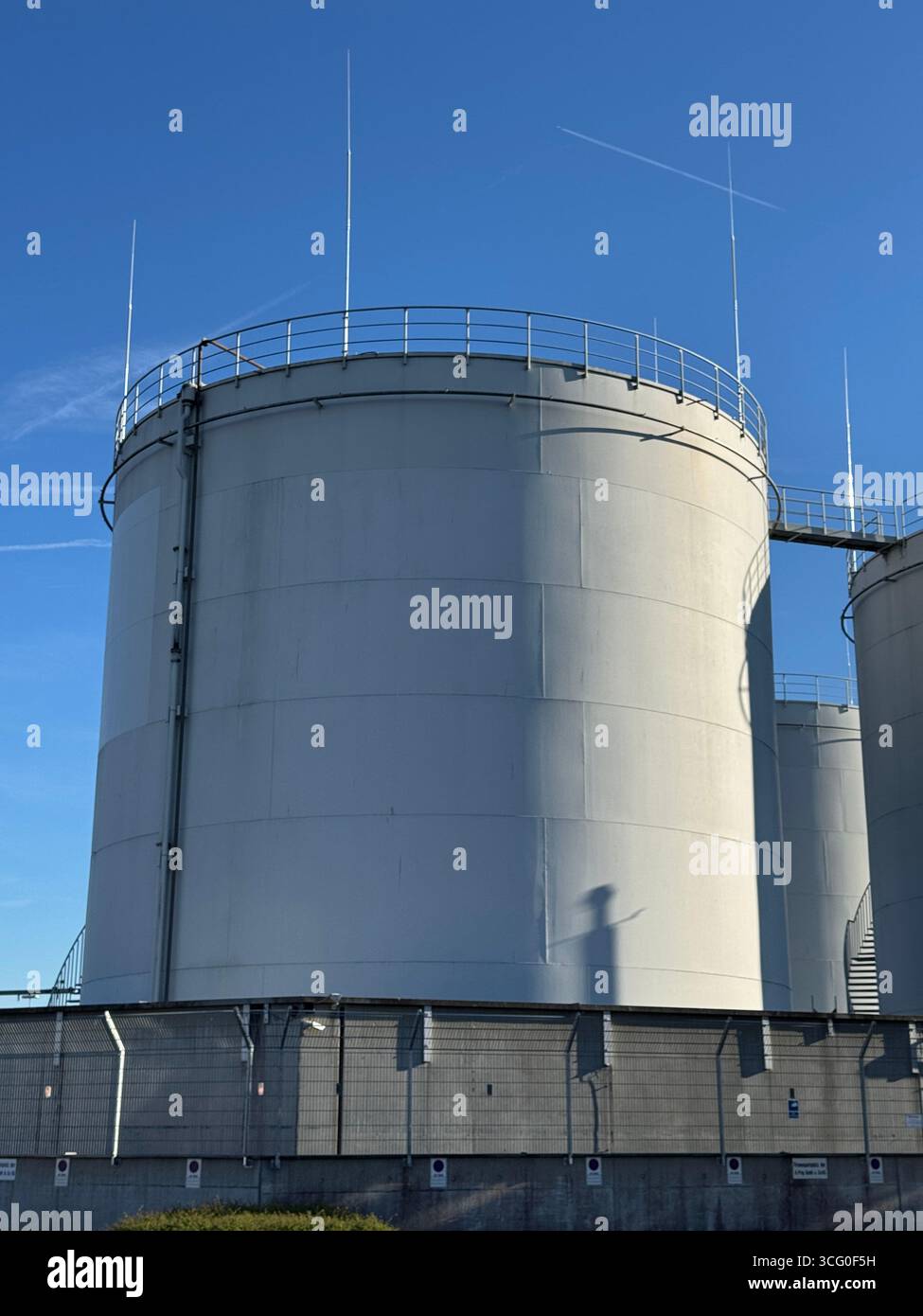 Large industrial storage tanks are situated under a clear blue sky ...