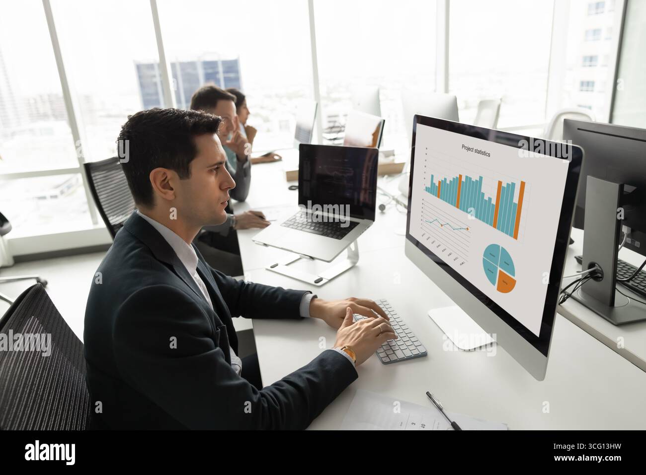 Data analyst focused on desktop monitor displaying project statistics ...