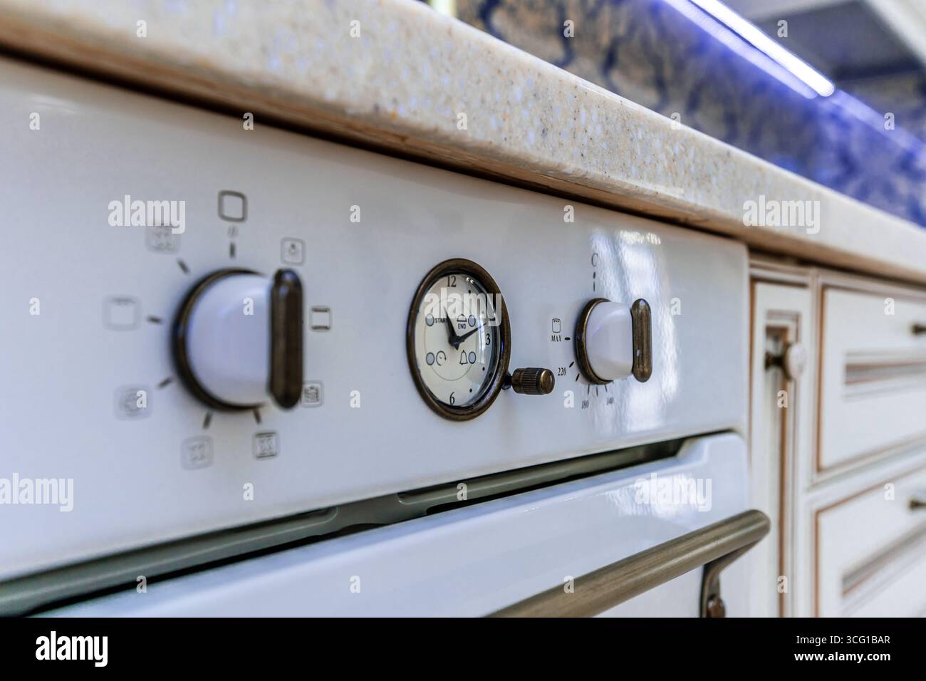 A white oven with a clock on the front. The oven has a dial on the ...
